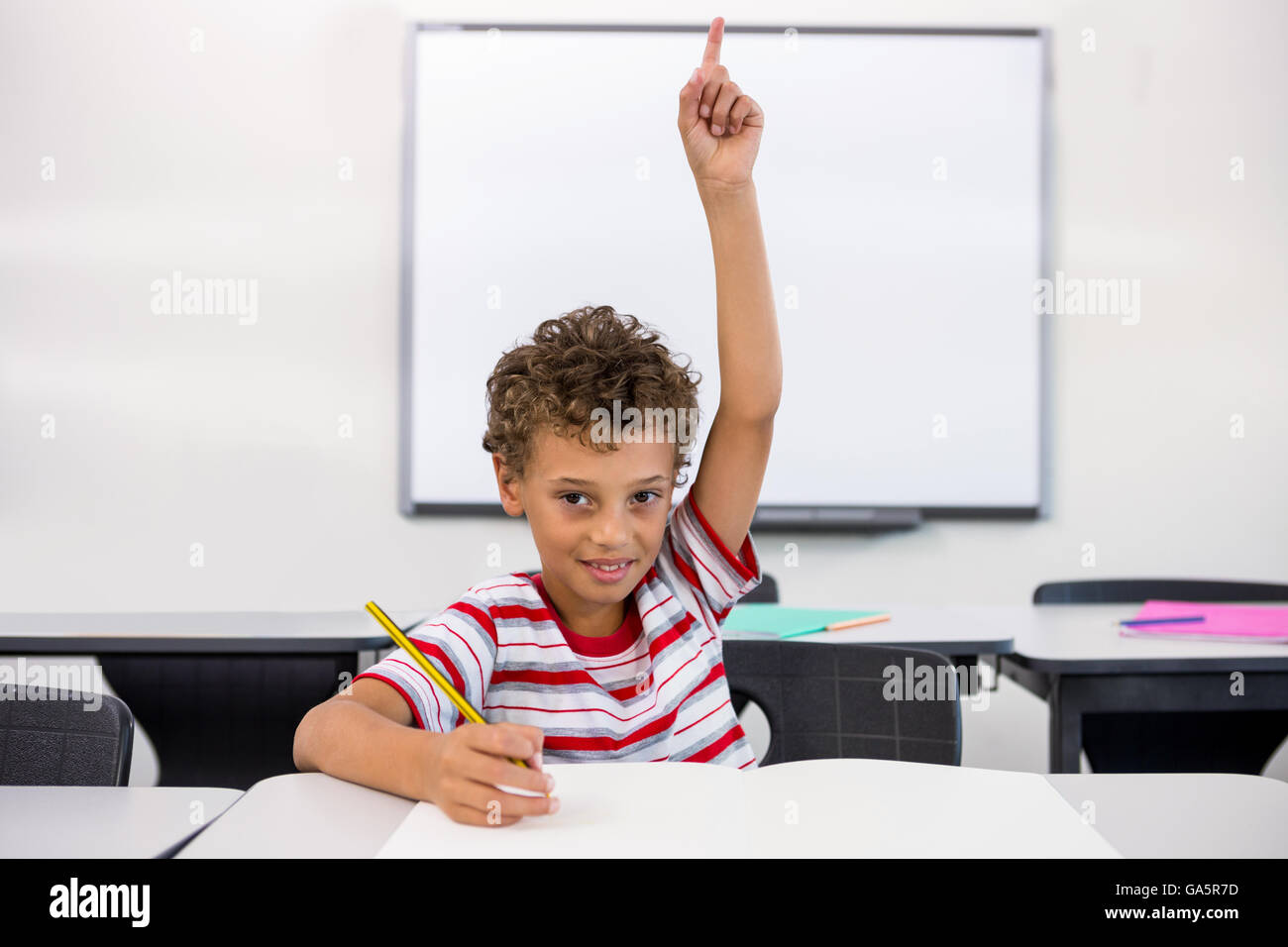 Boy raising hand in classroom hi-res stock photography and images - Alamy