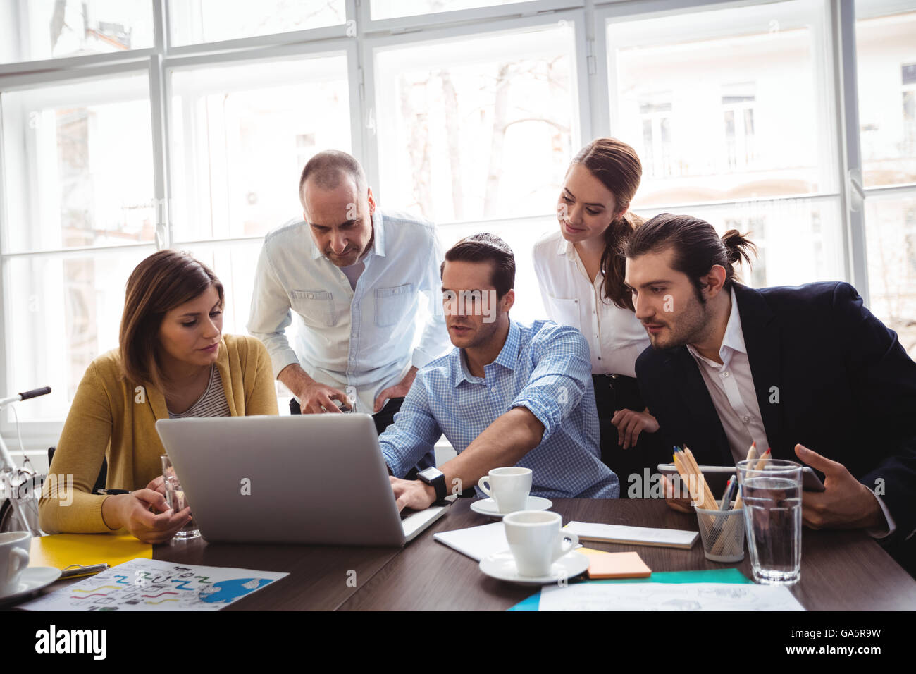 Creative business people looking at laptop Stock Photo - Alamy