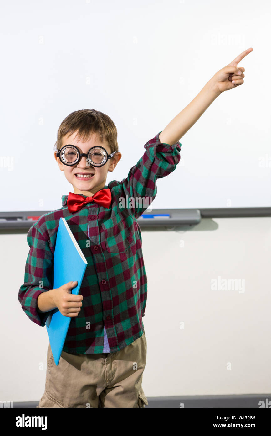 Portrait of cute boy with notebook pointing in classroom Stock Photo ...