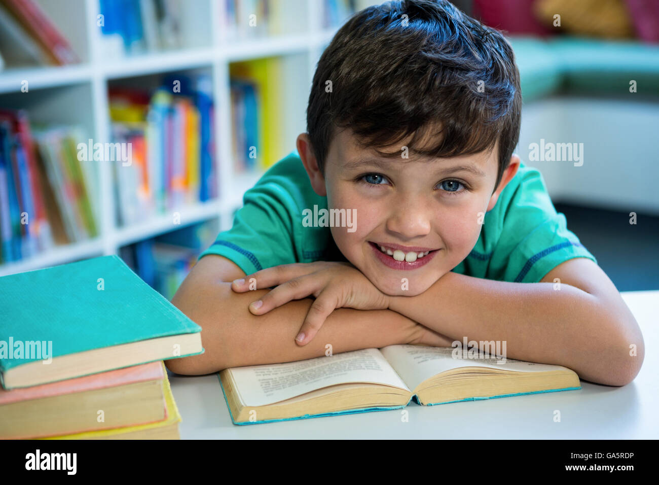 Smiling boy with book in school library Stock Photo - Alamy