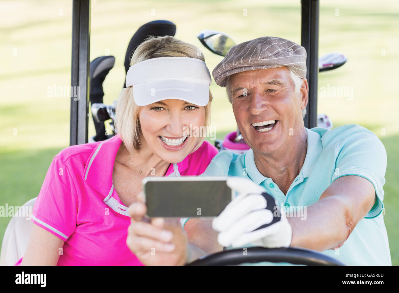Mature couple taking selfie while sitting in golf buggy Stock Photo - Alamy