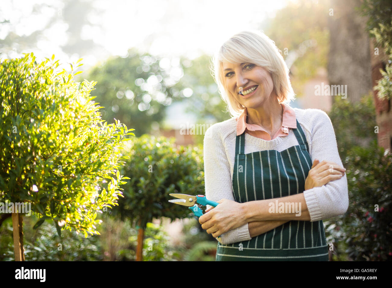 Confident female gardener standing by plants Stock Photo - Alamy