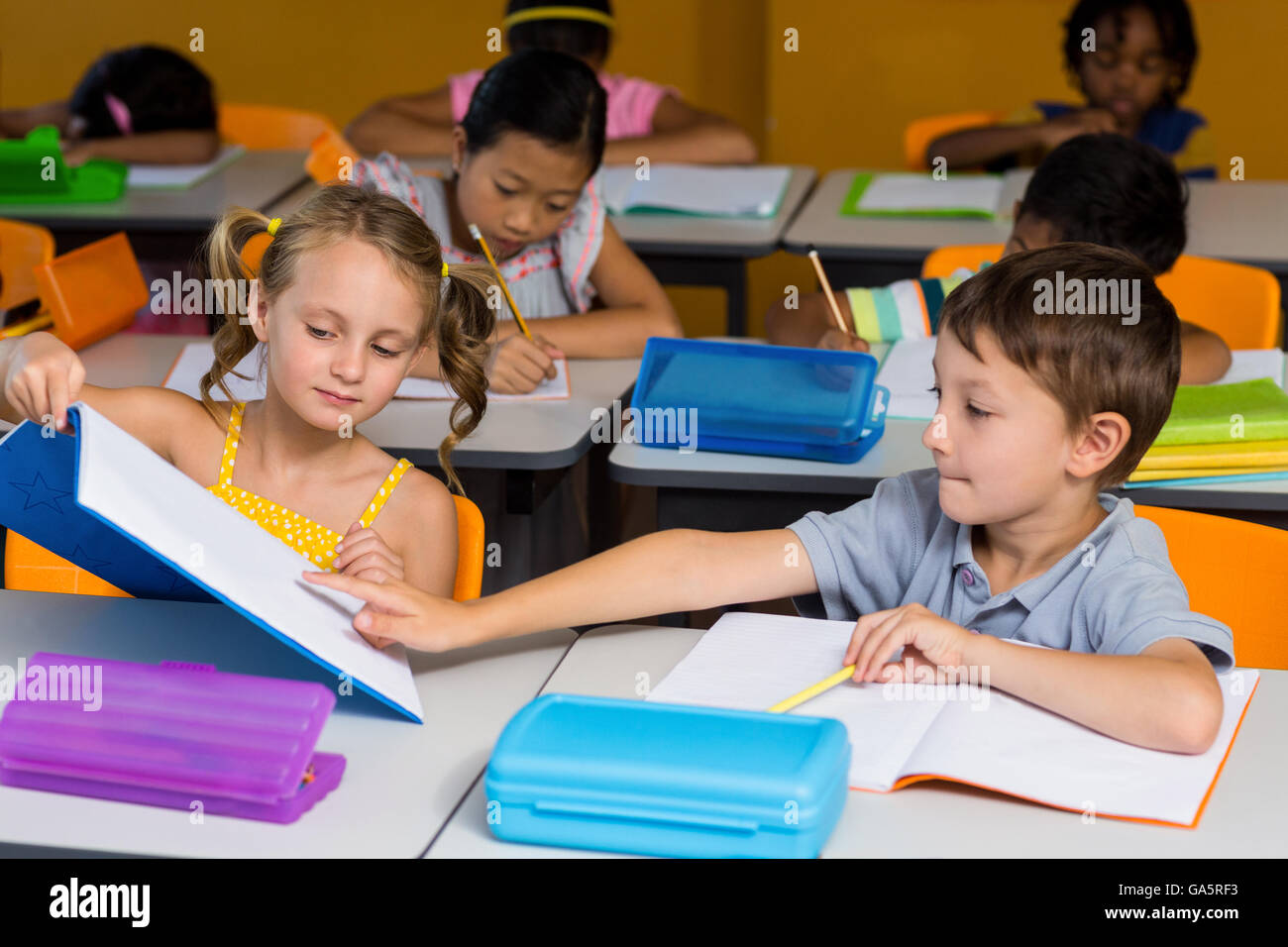 Boy pointing at book showed by classmate Stock Photo - Alamy