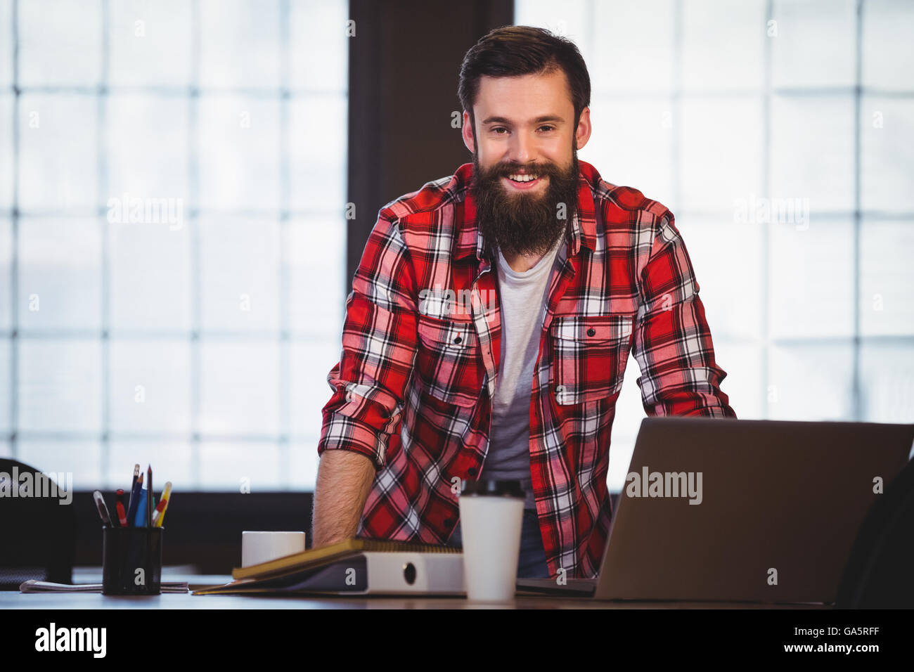 Confident hipster leaning on desk in creative office Stock Photo - Alamy