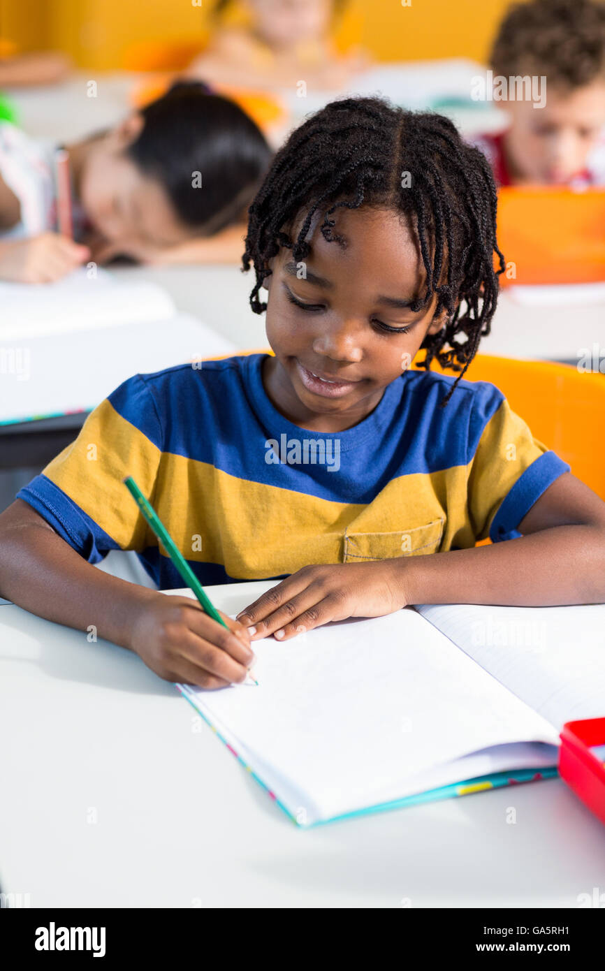 Cute boy writing on book Stock Photo - Alamy