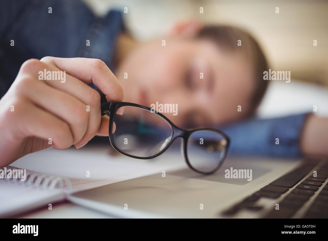 Tired businesswoman holding eyeglasses while taking nap in office Stock ...