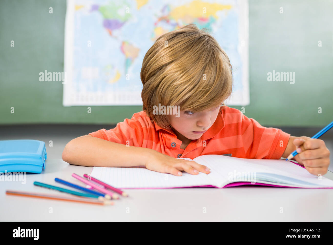 Boy writing on book in classroom Stock Photo - Alamy