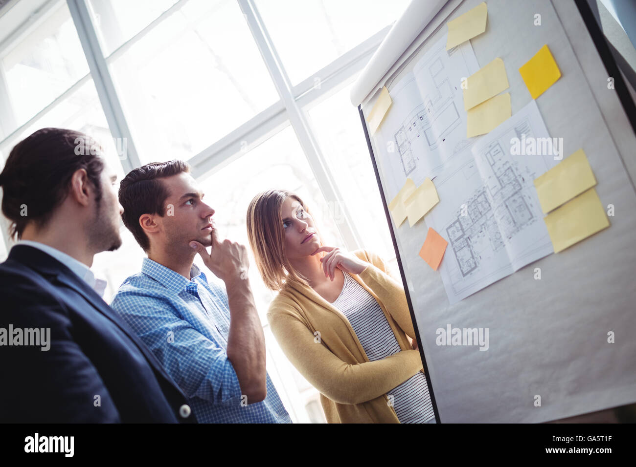 Thoughtful business people looking at blueprints Stock Photo - Alamy