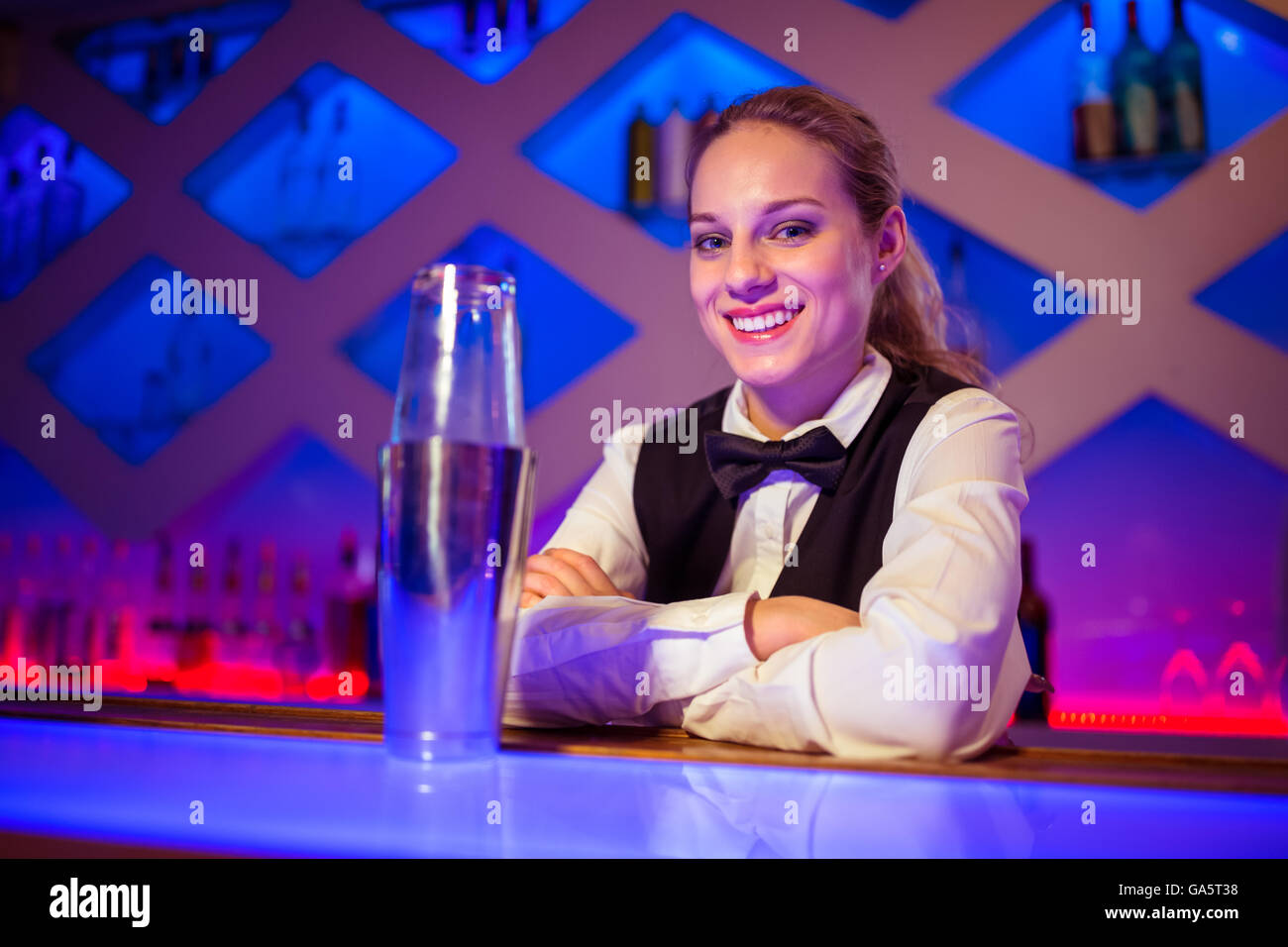 Confident barmaid sitting by cocktail shaker at counter Stock Photo - Alamy