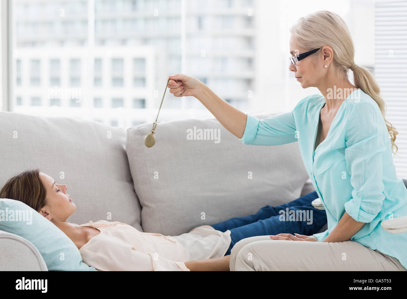 Hypnotherapist holding pendulum by patient Stock Photo - Alamy