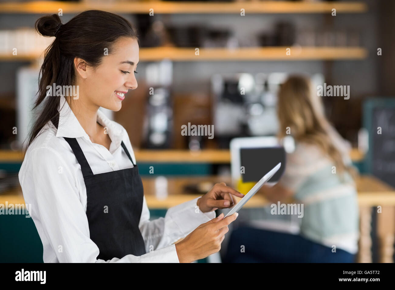 Smiling waitress using digital tablet Stock Photo - Alamy