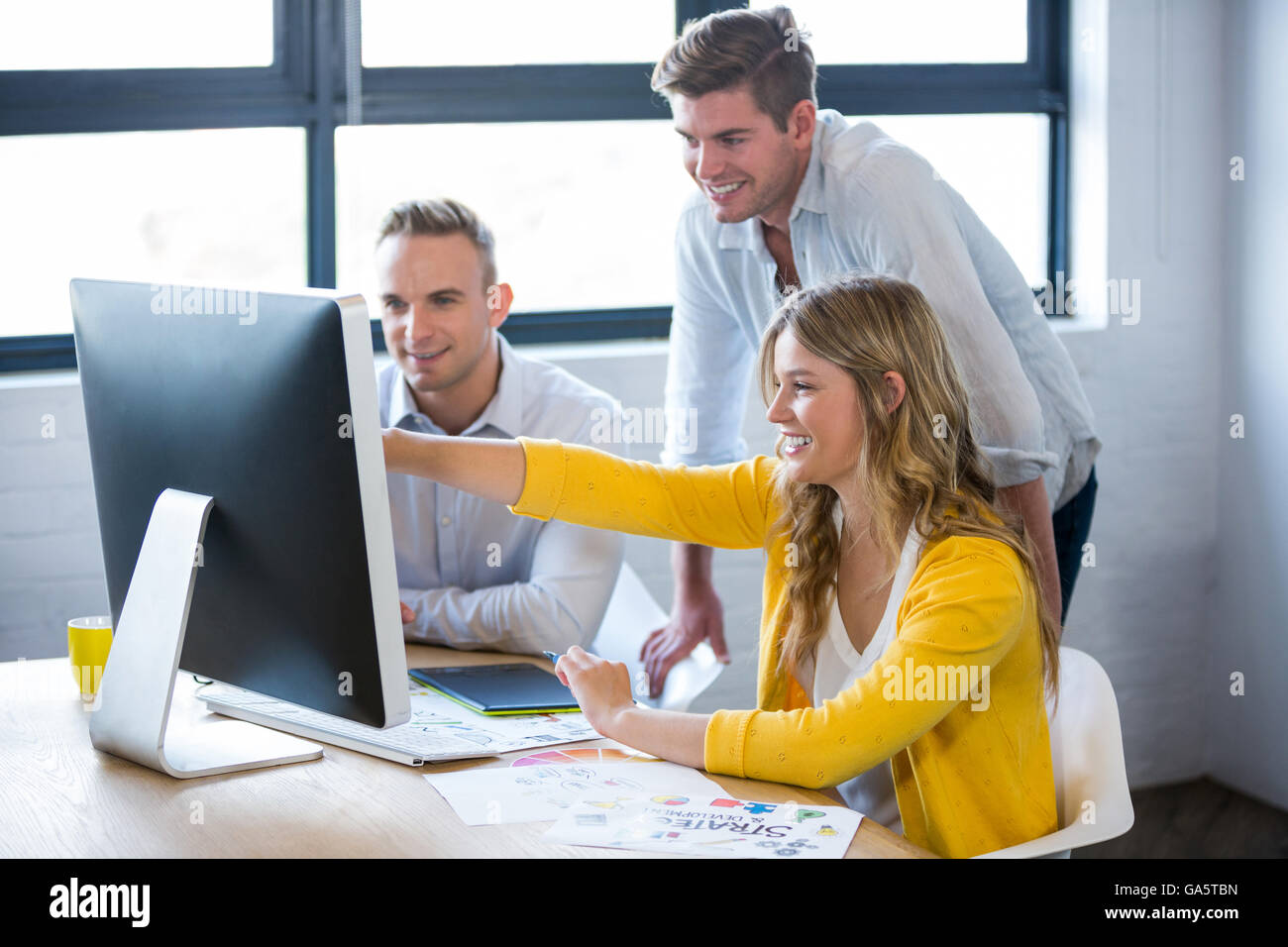 Smiling business people discussing over computer Stock Photo - Alamy