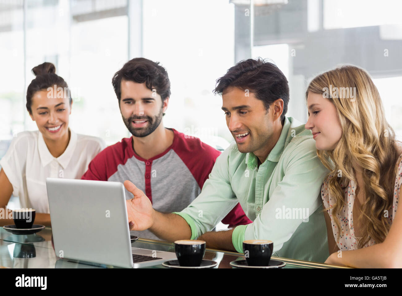 Group of friends using laptop while having cup of coffee Stock Photo ...