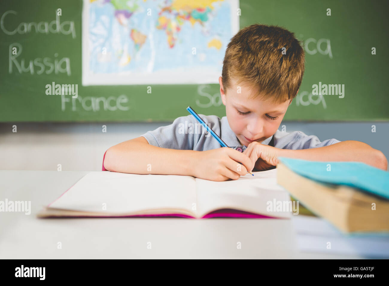 Schoolboy doing homework in classroom Stock Photo - Alamy