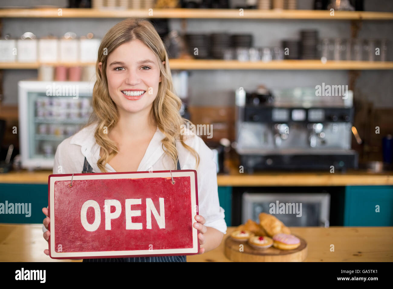 Smiling waitress showing signboard with open sign at cafe Stock Photo ...