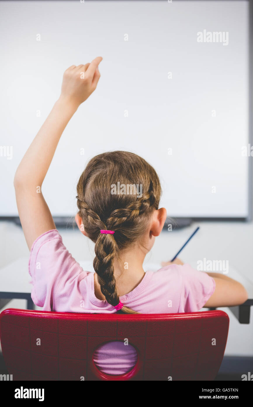 Rear view of schoolgirl raising her hand in classroom Stock Photo - Alamy