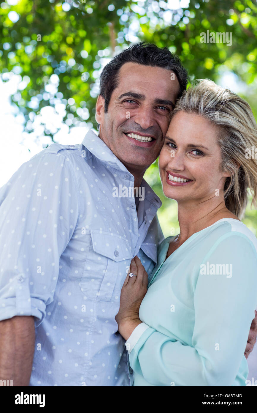 Couple embracing while standing against trees Stock Photo - Alamy