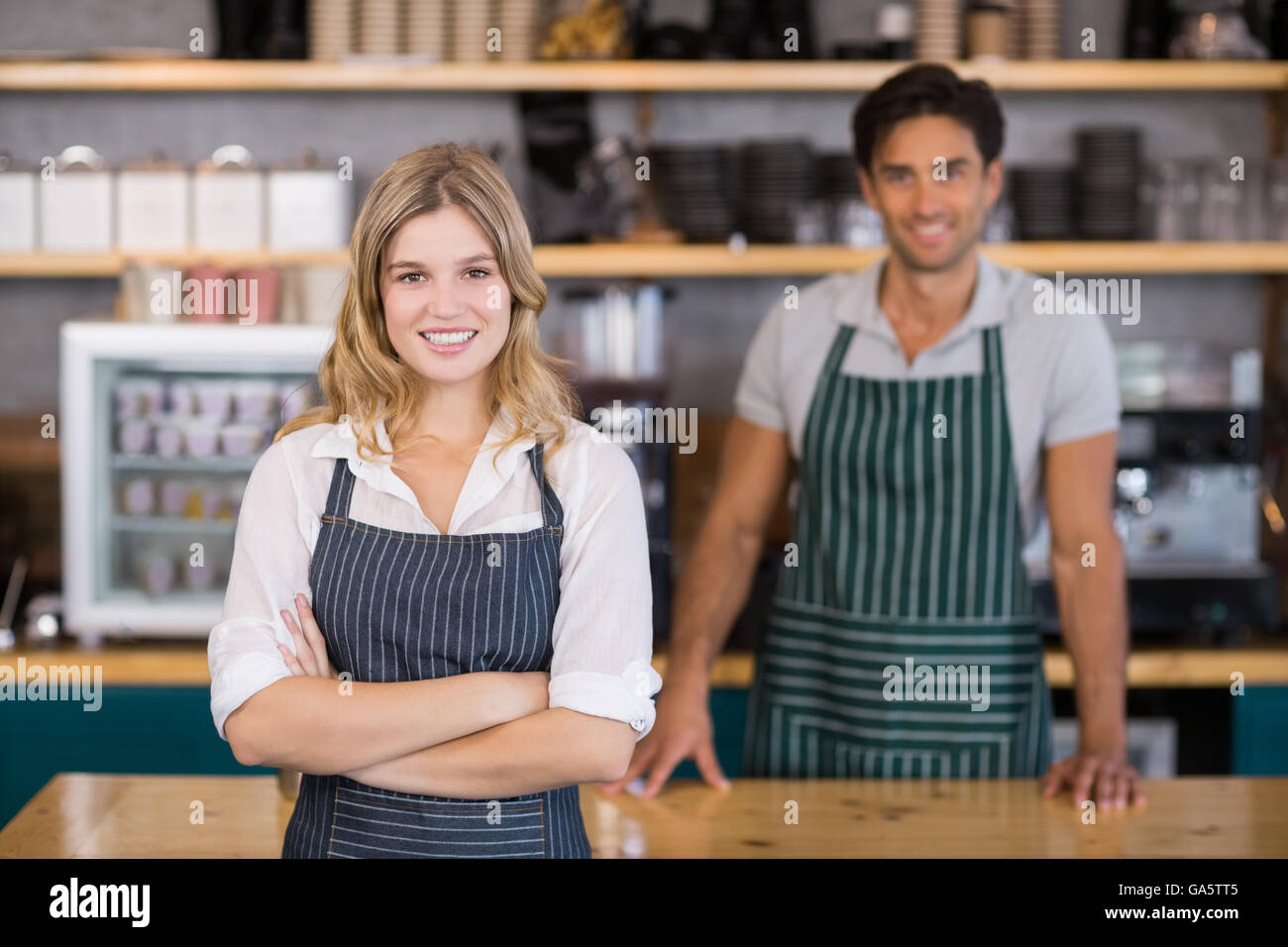 Portrait of smiling waitress standing with arms crossed Stock Photo - Alamy