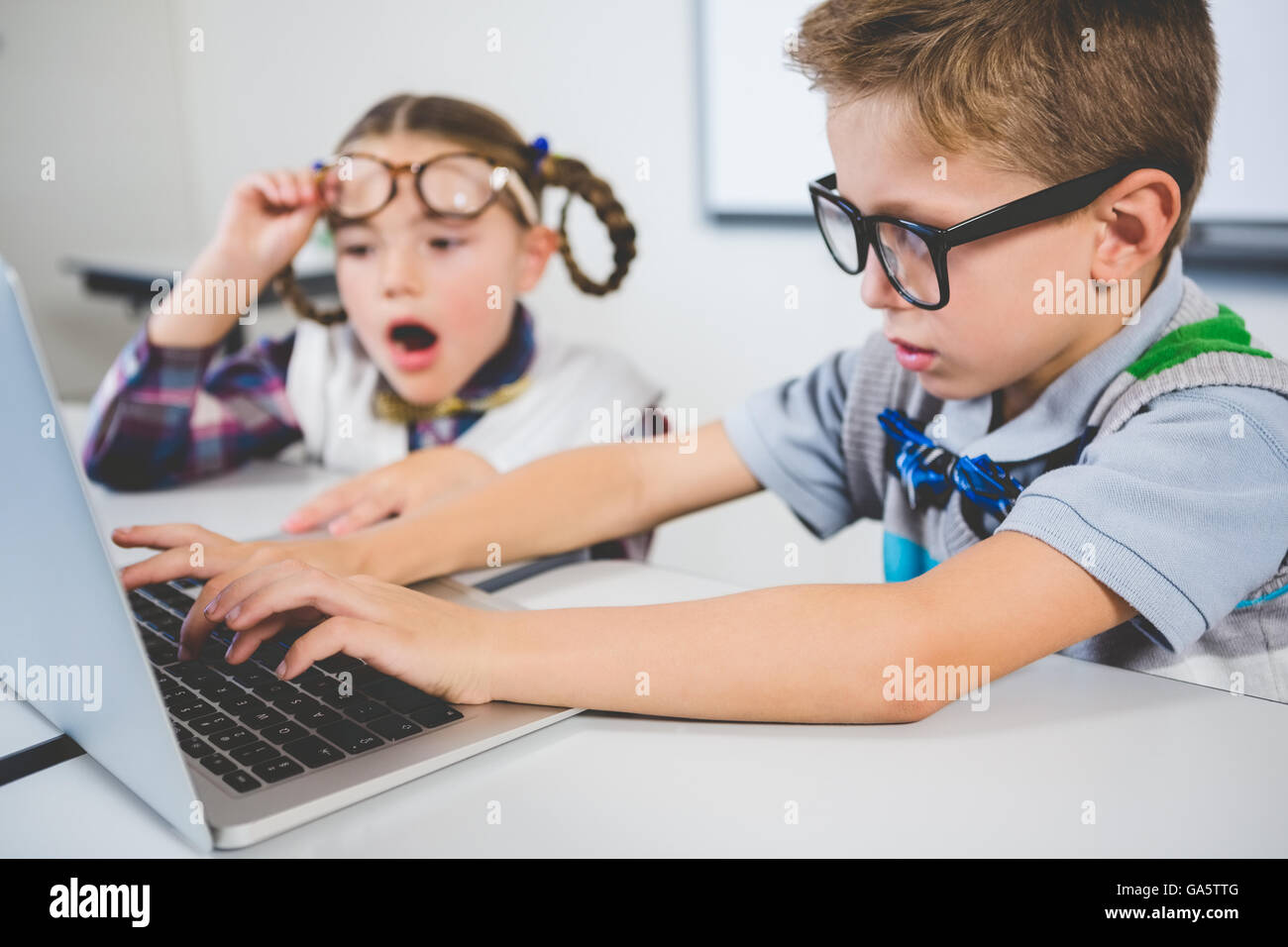 School kids using a laptop in classroom Stock Photo - Alamy