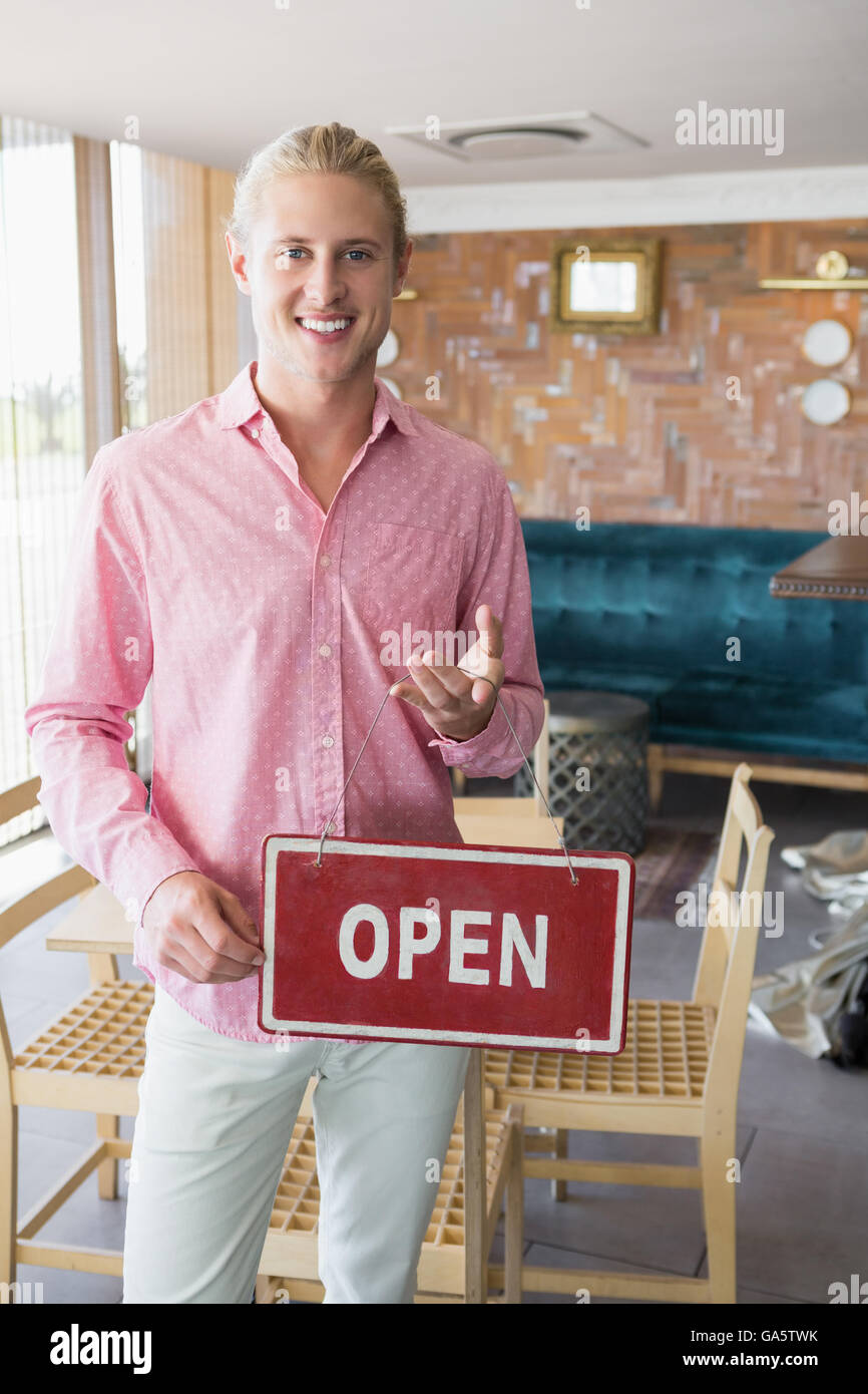 Restaurant manager holding open signboard Stock Photo - Alamy