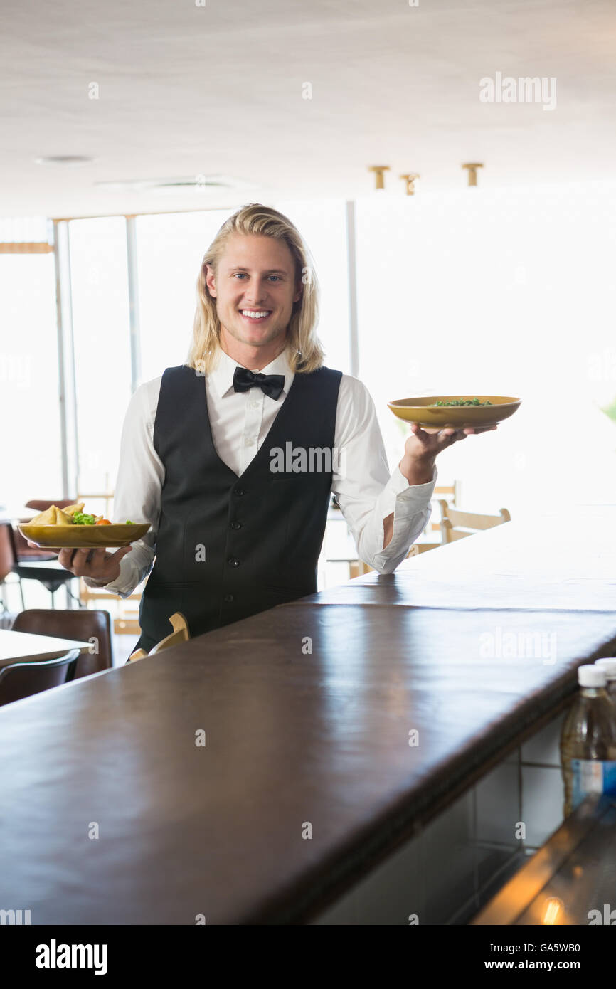 Waiter holding plated meals in restaurant Stock Photo - Alamy