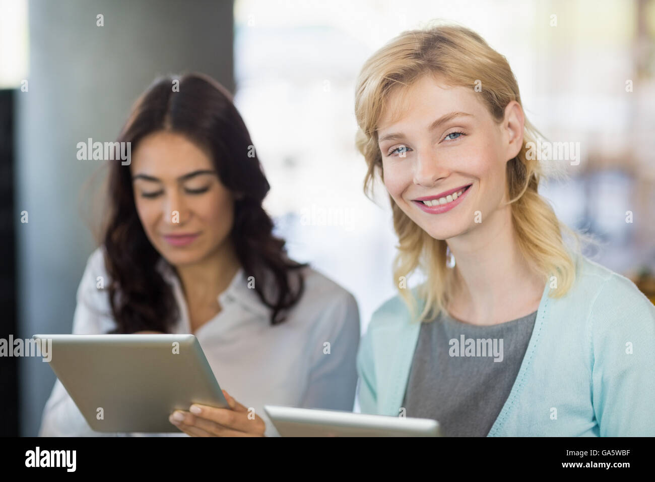 Two beautiful women using digital tablet Stock Photo - Alamy