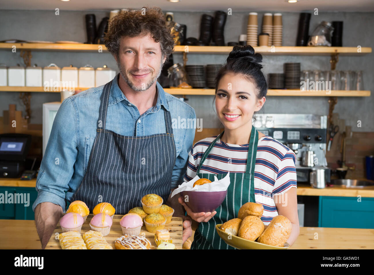 Waiter and waitress holding wooden tray and bowl with snacks and ...