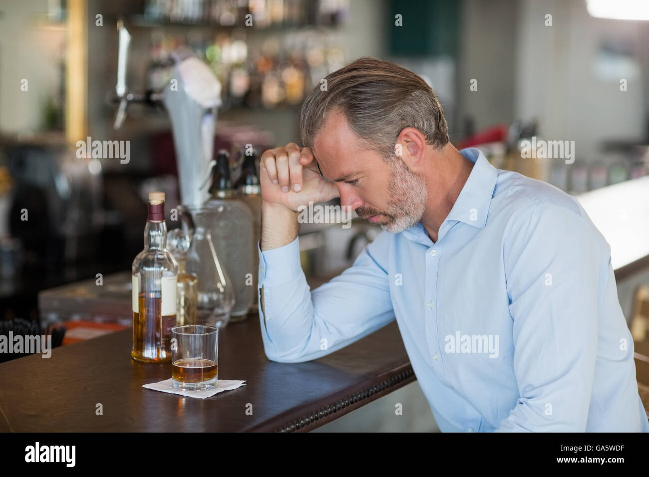 Tired man leaning his elbow on the counter Stock Photo - Alamy