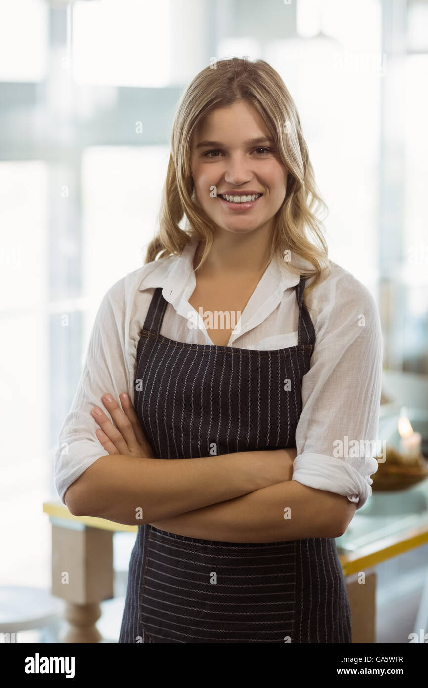 Portrait of smiling waitress standing with arms crossed Stock Photo - Alamy