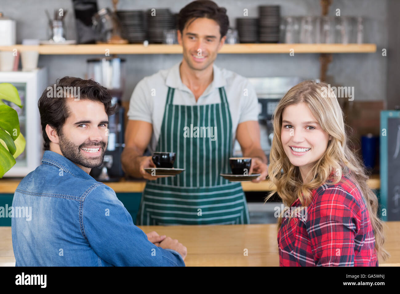Waiter offering coffee to a couple Stock Photo - Alamy