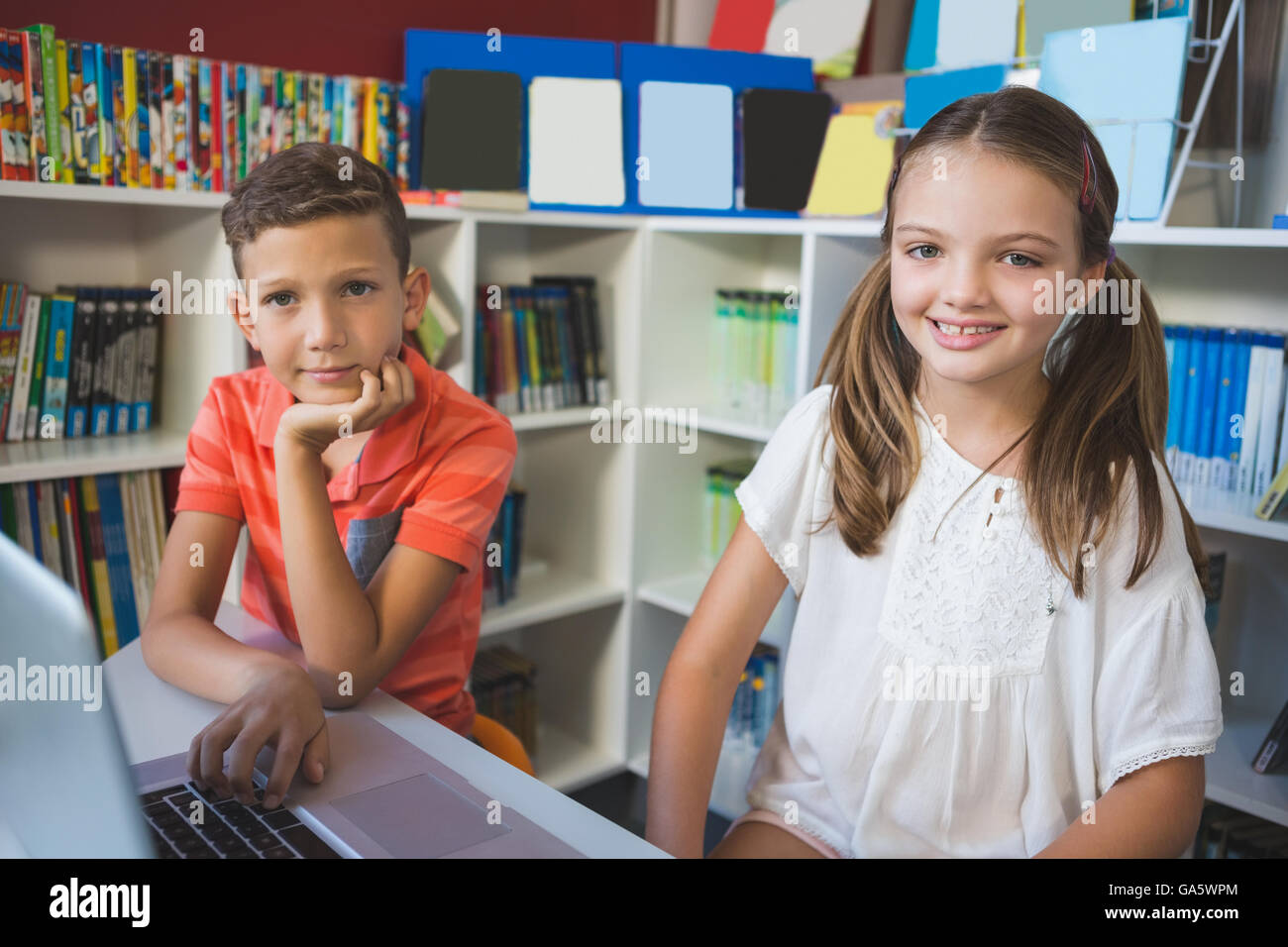 School kids using a laptop in library Stock Photo - Alamy
