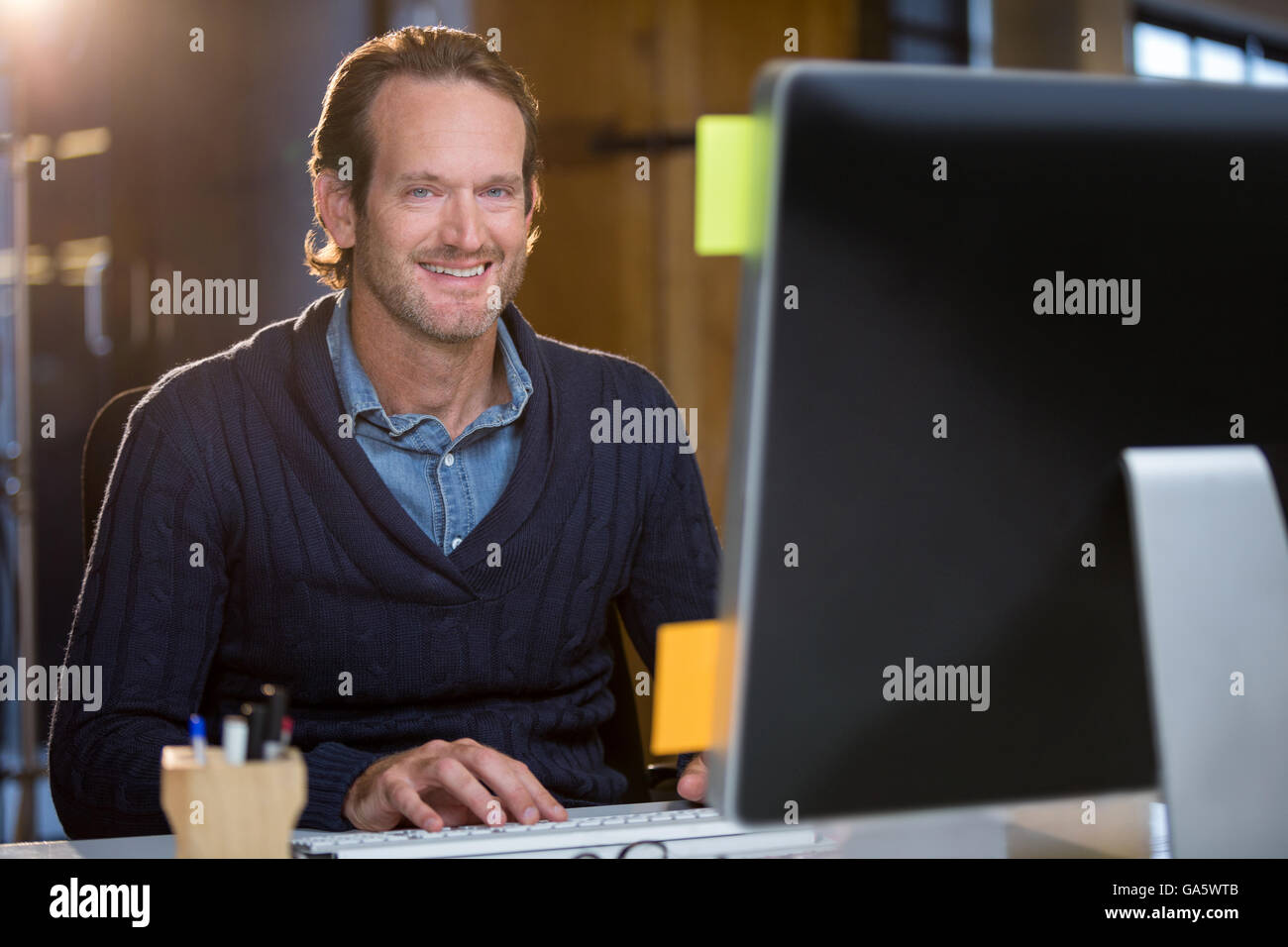 Confident businessman using computer at desk Stock Photo - Alamy
