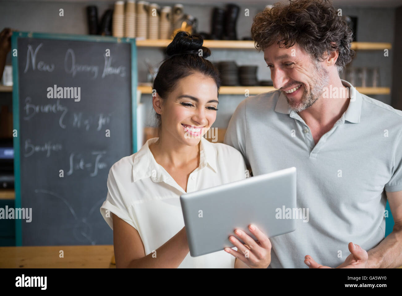 Waiter and waitress discussing over digital tablet Stock Photo - Alamy