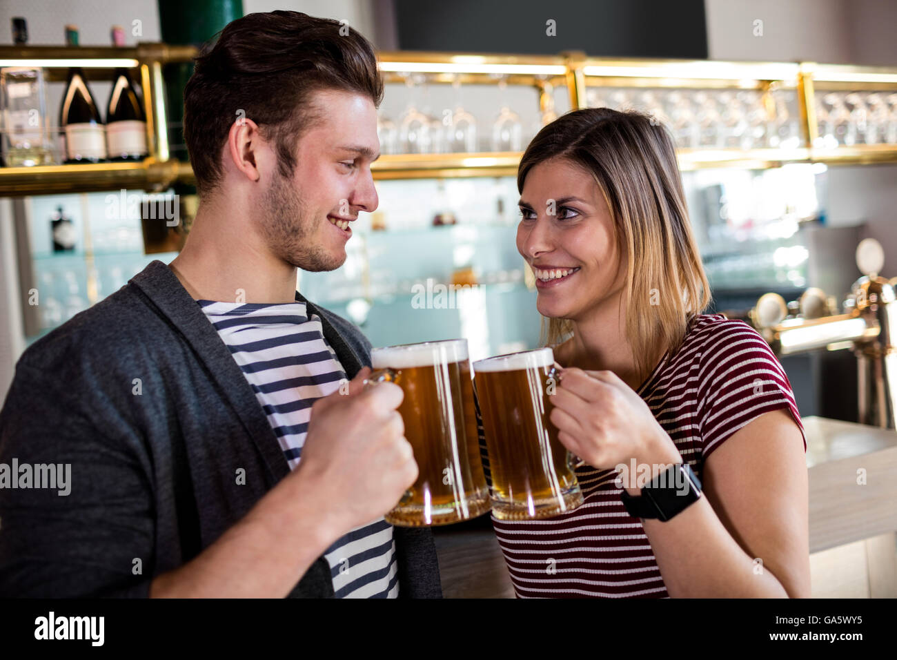 Happy young couple toasting beer mug Stock Photo - Alamy