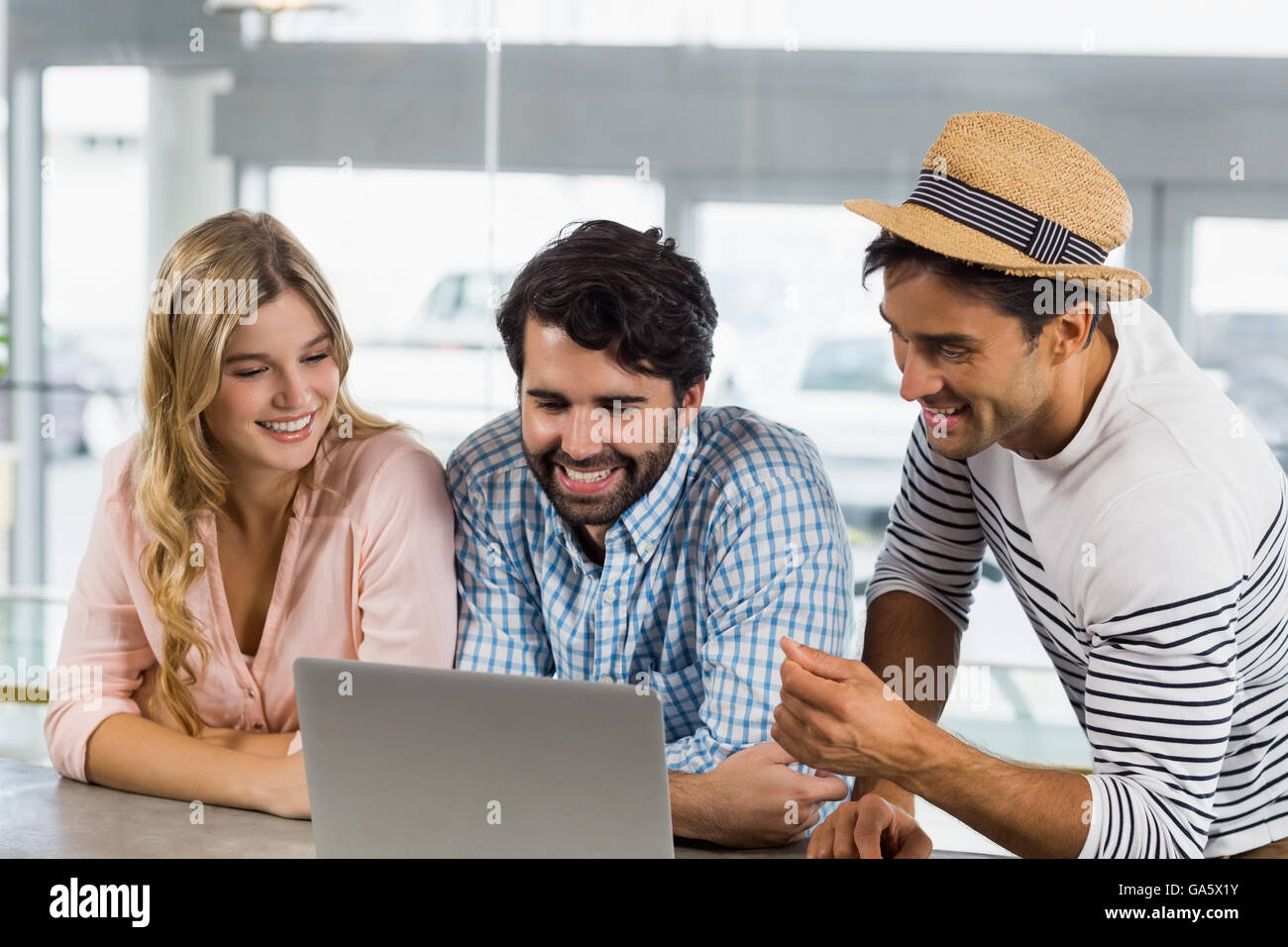 Smiling woman and two men using laptop Stock Photo - Alamy