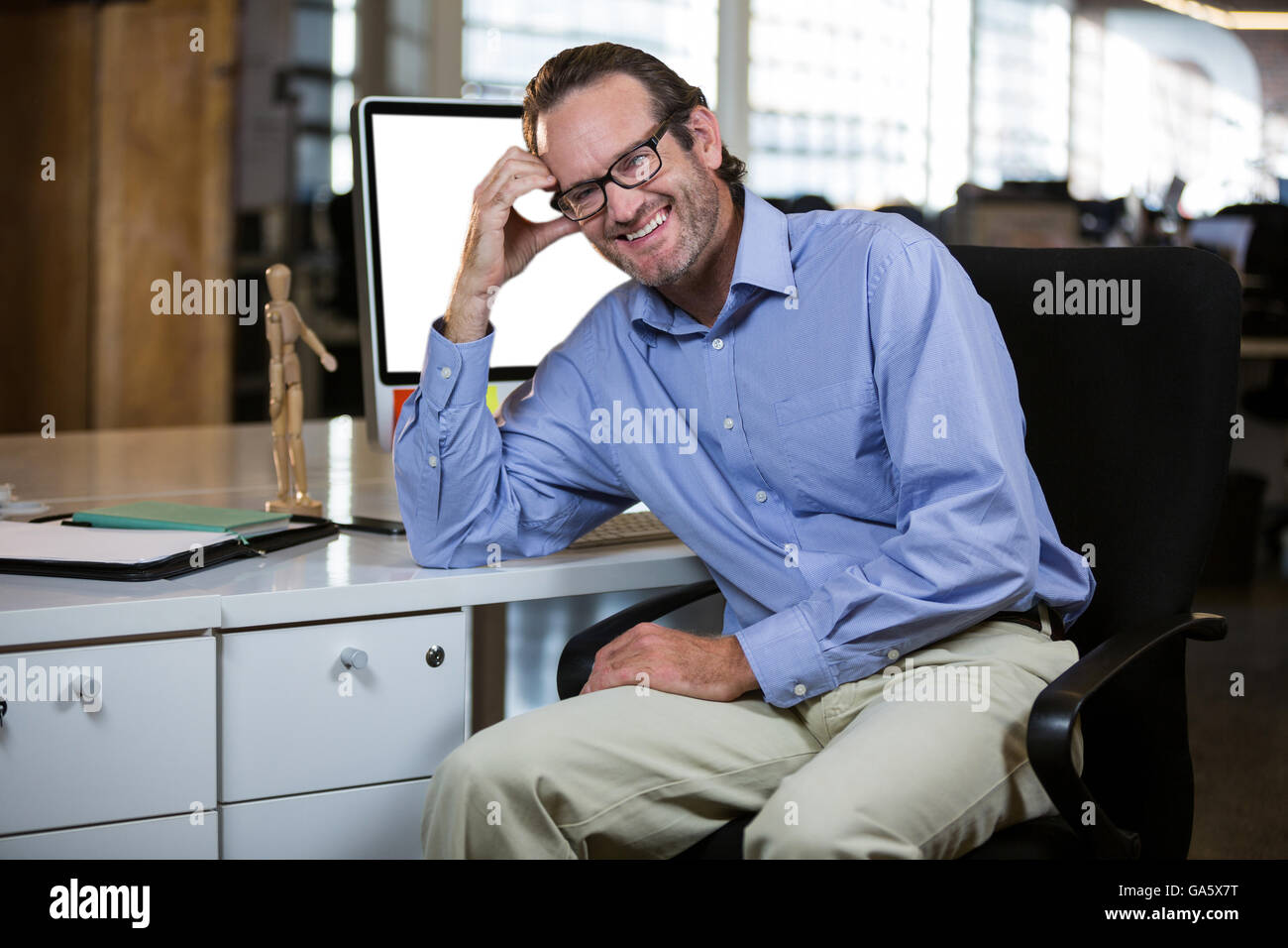 Creative businessman leaning at computer desk Stock Photo - Alamy