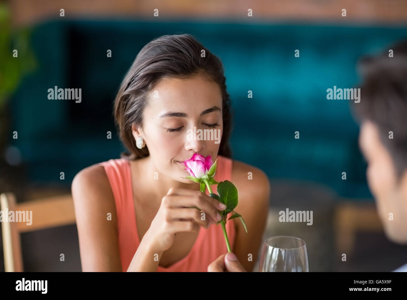 Woman smelling a rose offered by man Stock Photo - Alamy