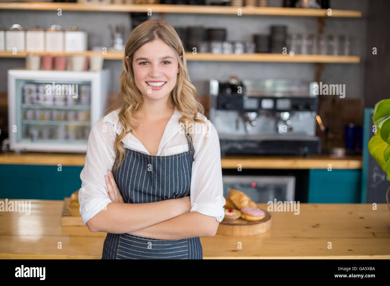 Portrait of smiling waitress standing with arms crossed Stock Photo - Alamy