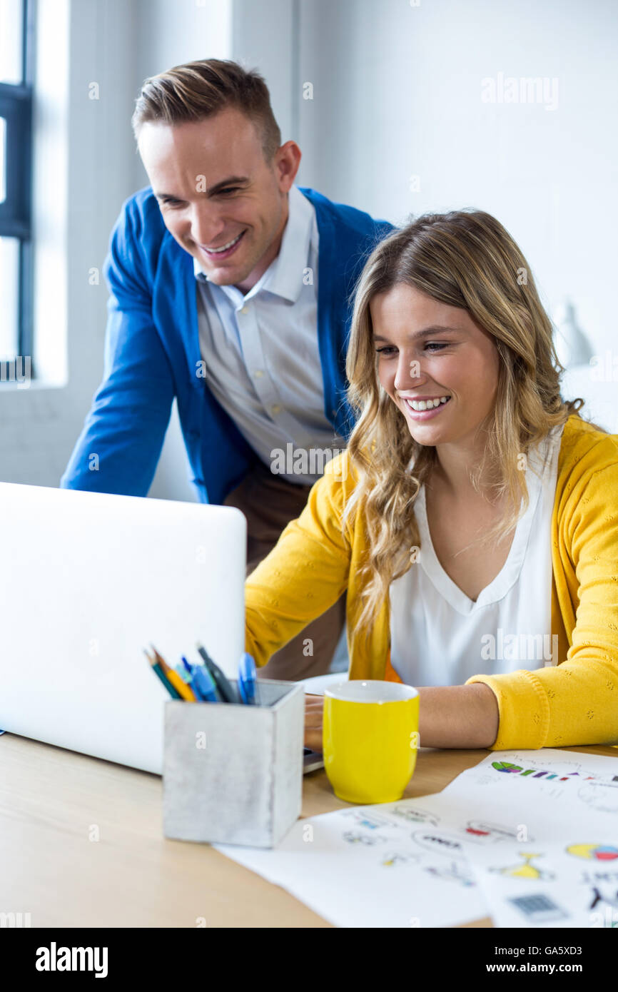 Smiling colleagues using laptop in office Stock Photo - Alamy
