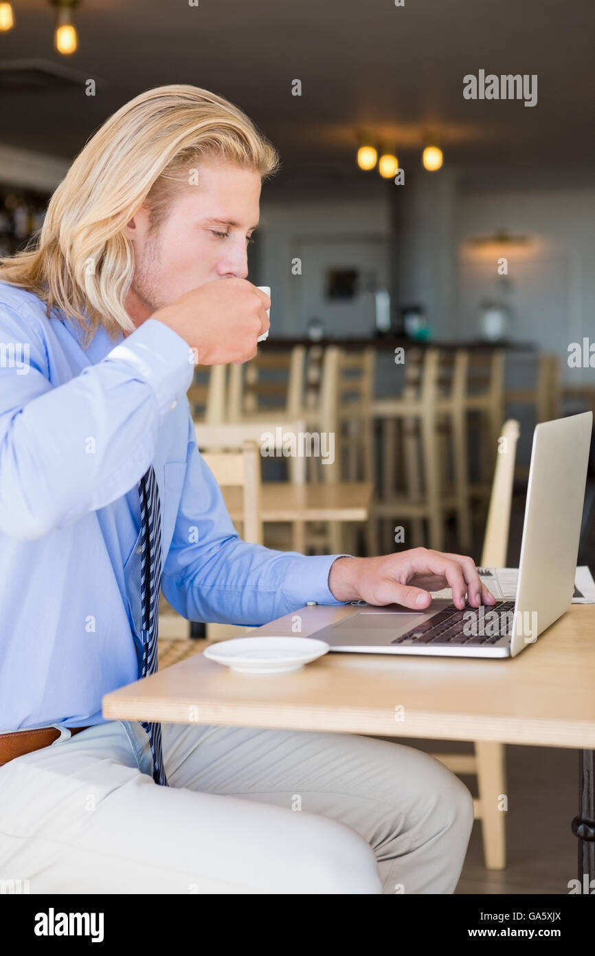 Man having coffee while using laptop Stock Photo - Alamy
