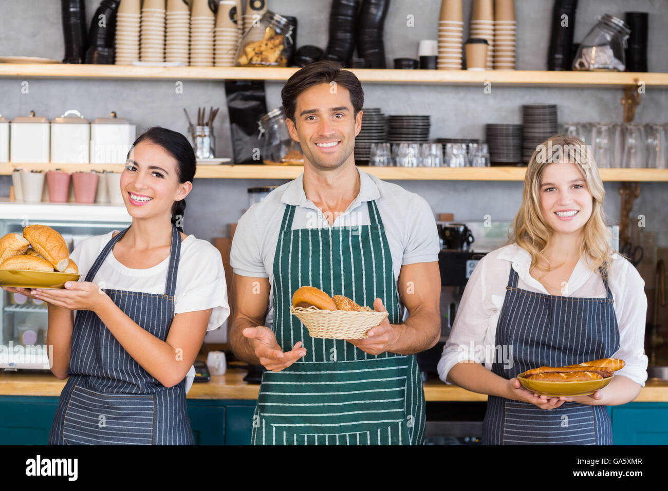 Smiling waiter and two waitresses holding plate of bread rolls Stock ...