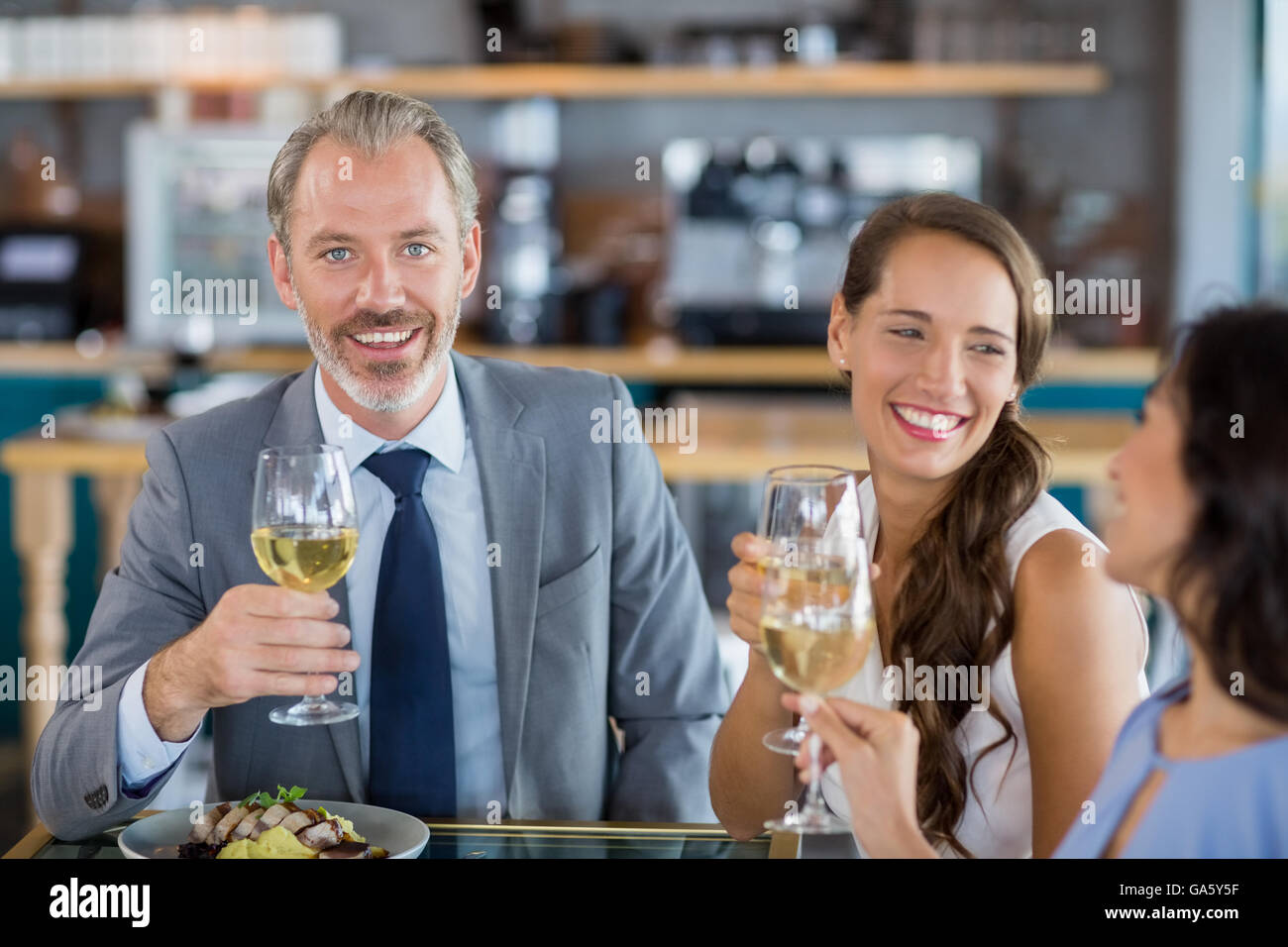 Businessman smiling at camera while colleague toasting glasses of wine ...