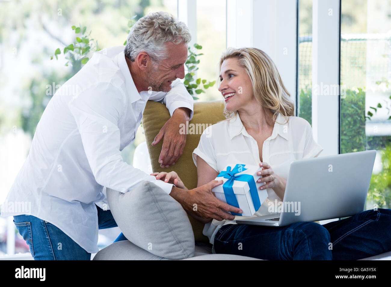 Happy man giving gift to woman with laptop Stock Photo - Alamy
