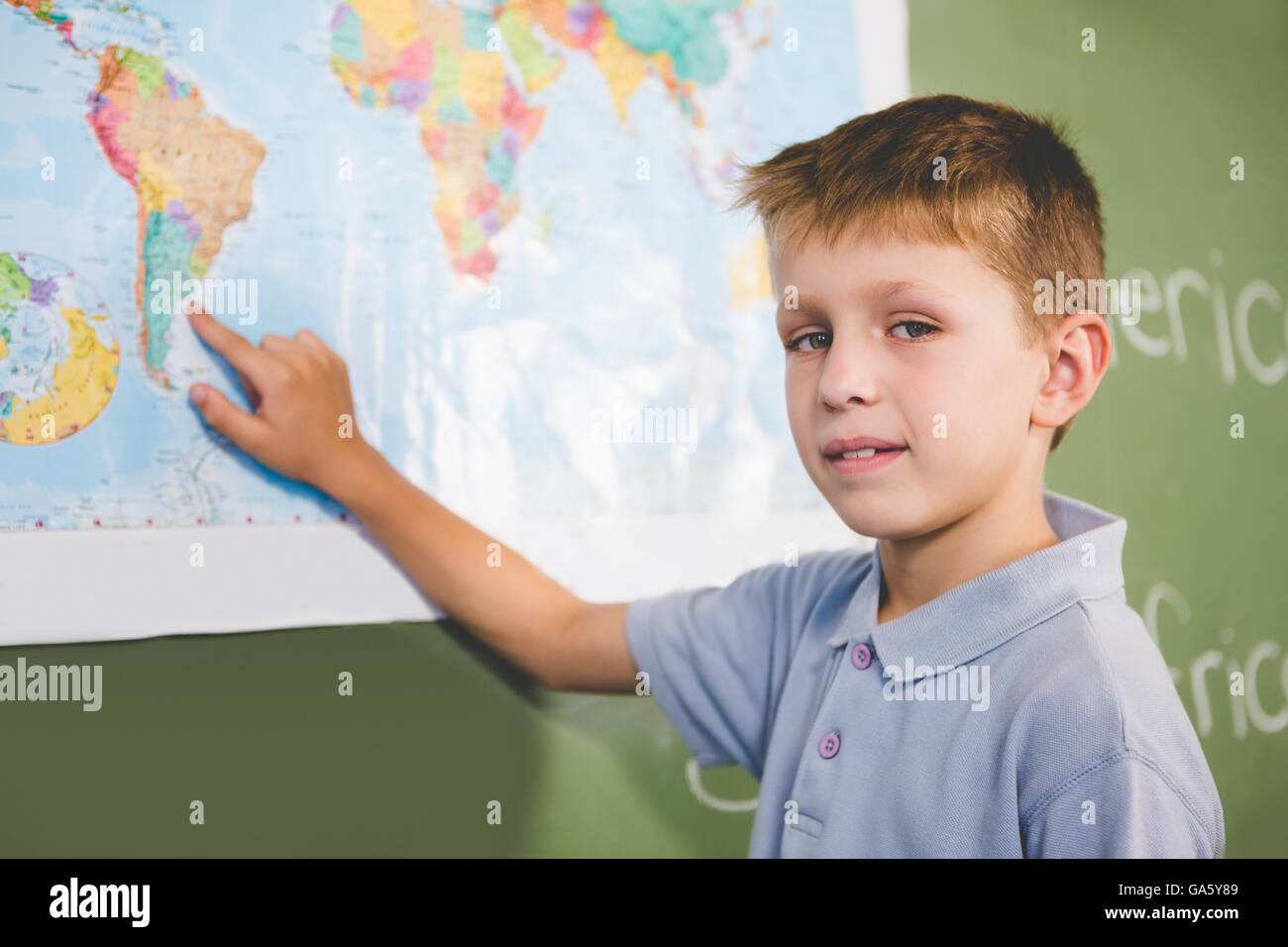 Portrait of schoolboy pointing at map in classroom Stock Photo - Alamy