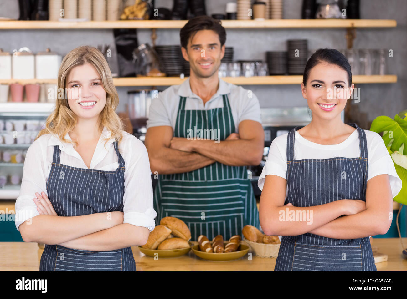 Smiling waiter and two waitresses standing with arms crossed Stock ...