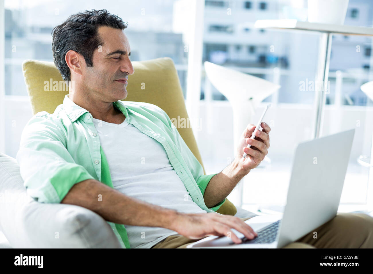 Man using cellphone on couch Stock Photo - Alamy