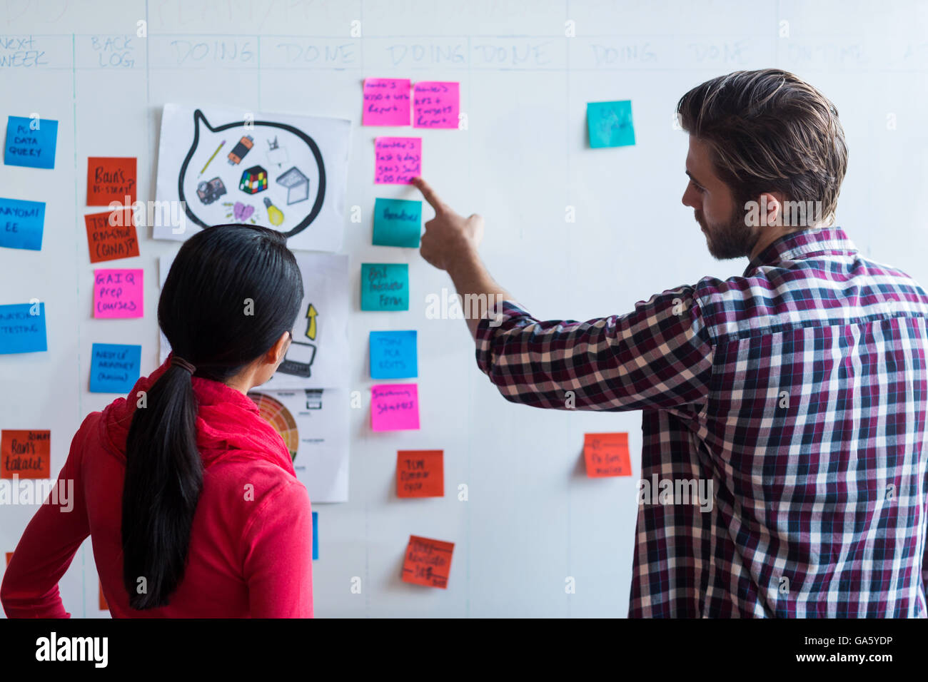 Colleagues discussing about sticky notes in office Stock Photo - Alamy