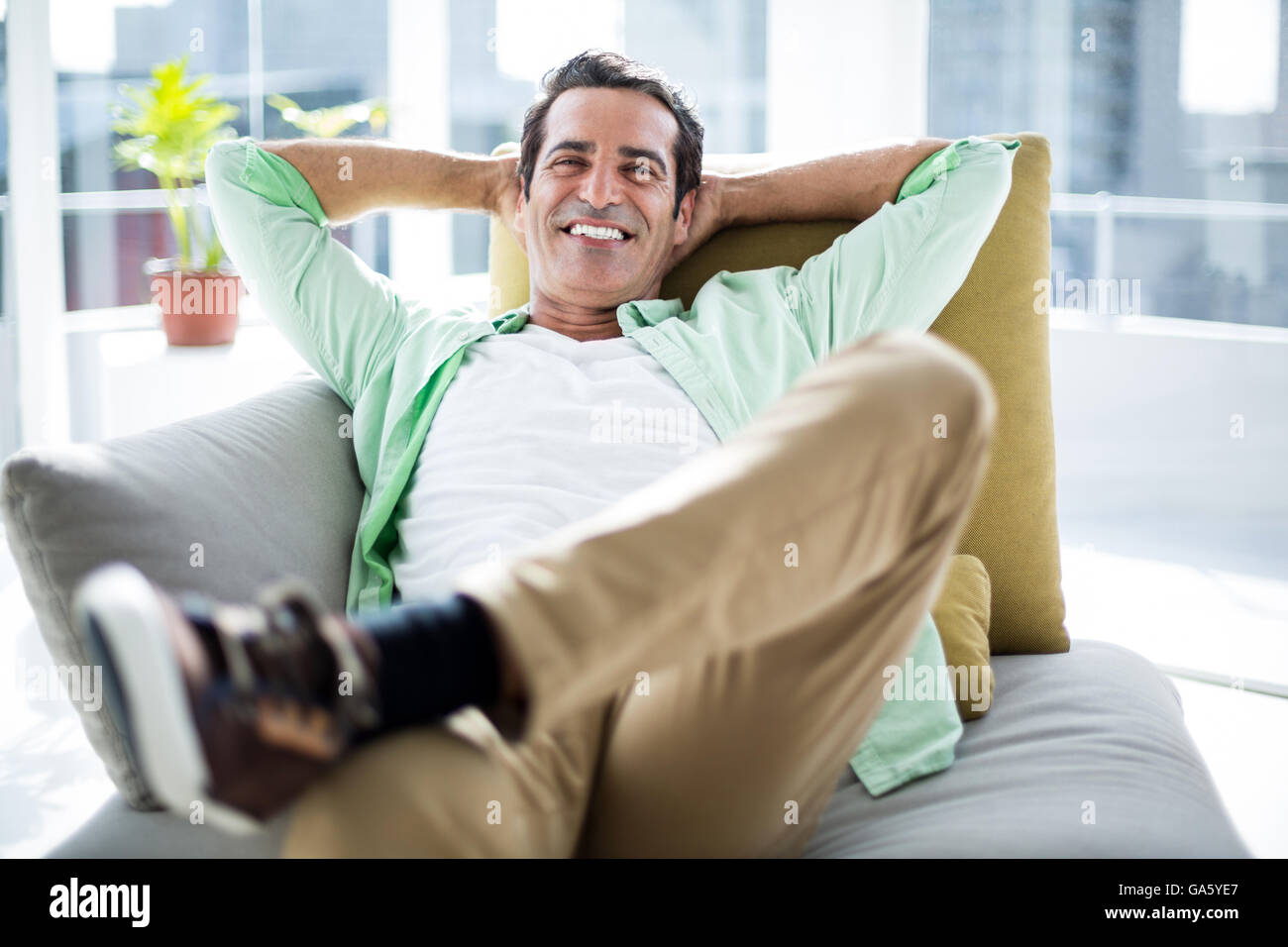 Happy man relaxing on sofa at home Stock Photo - Alamy