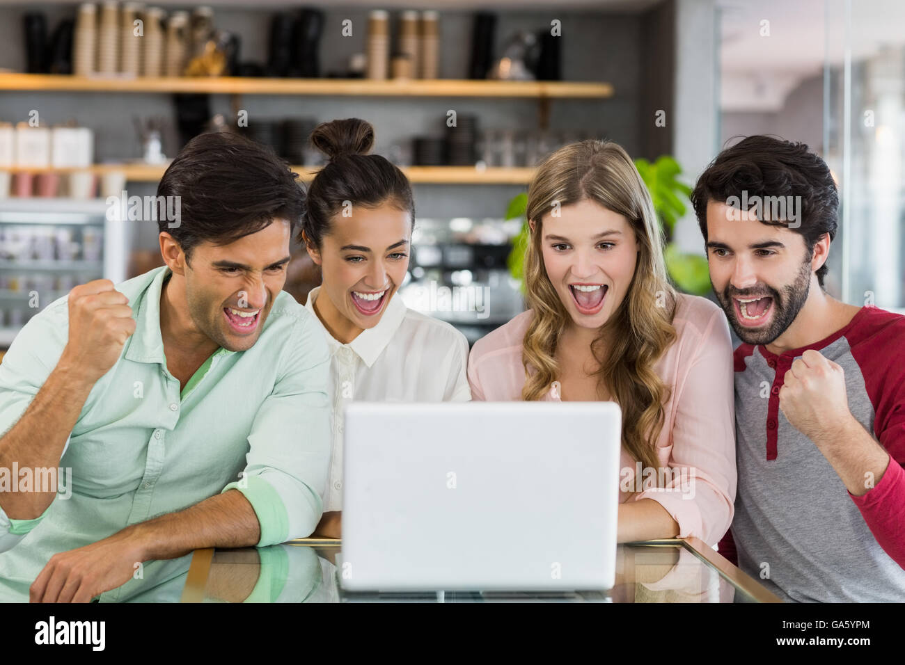 Group of excited friends using laptop Stock Photo - Alamy