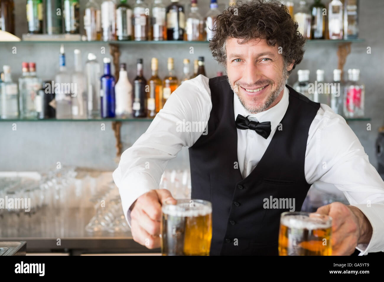 Waiter serving mug of beers Stock Photo - Alamy